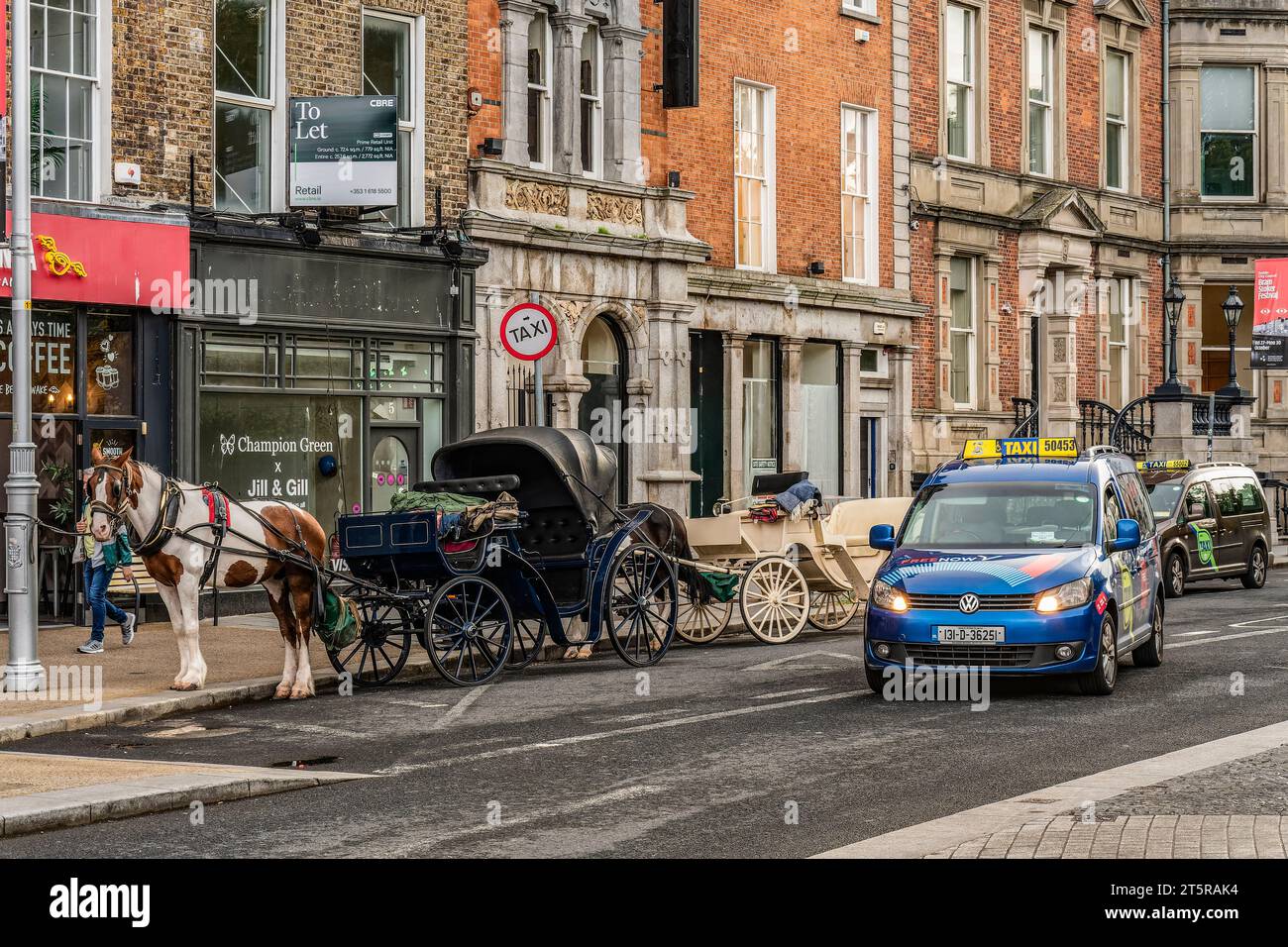 Taxi concept. Horse carriages and taxi cars beside St. Stephens Green ...