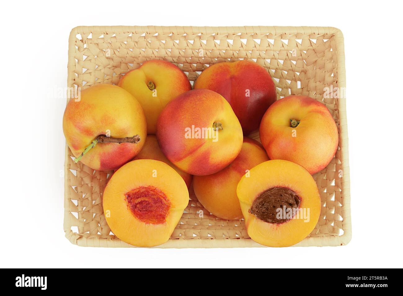 Ripe nectarine fruit with half in a wicker basket isolated on white ...