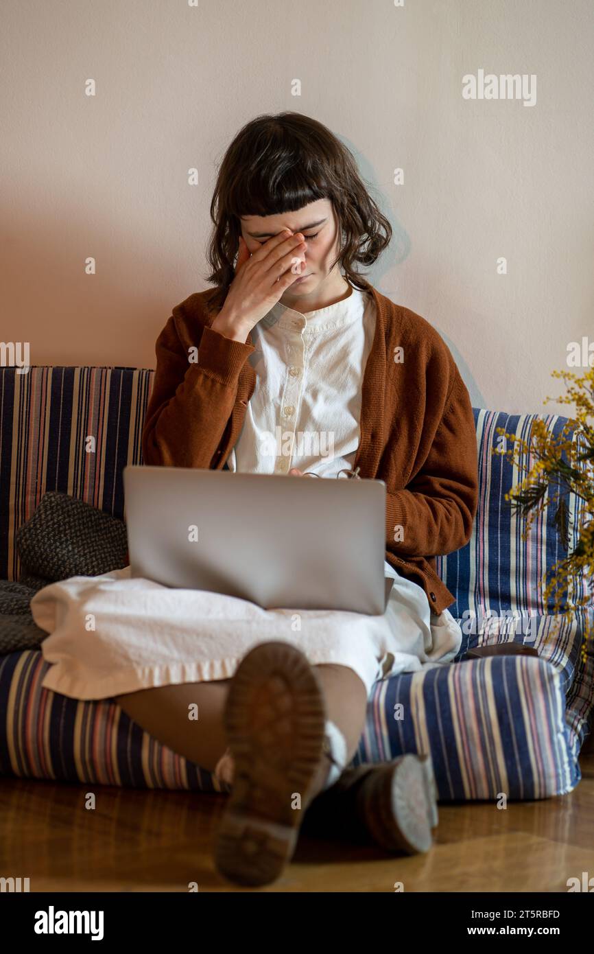 Tired teenage hipster girl working, studying with laptop from home ...