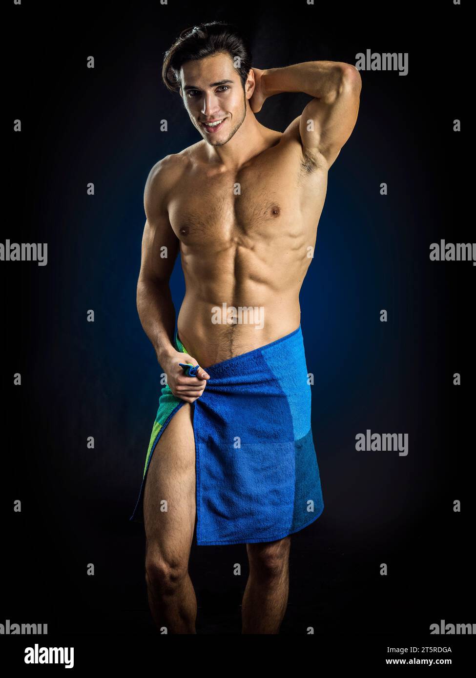A young attractive man with a towel wrapped around his muscular body. Photo of a man wrapped in ...