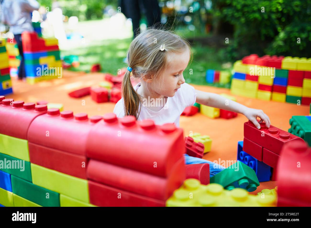 Adorable preschooler girl playing with large colorful plastic ...