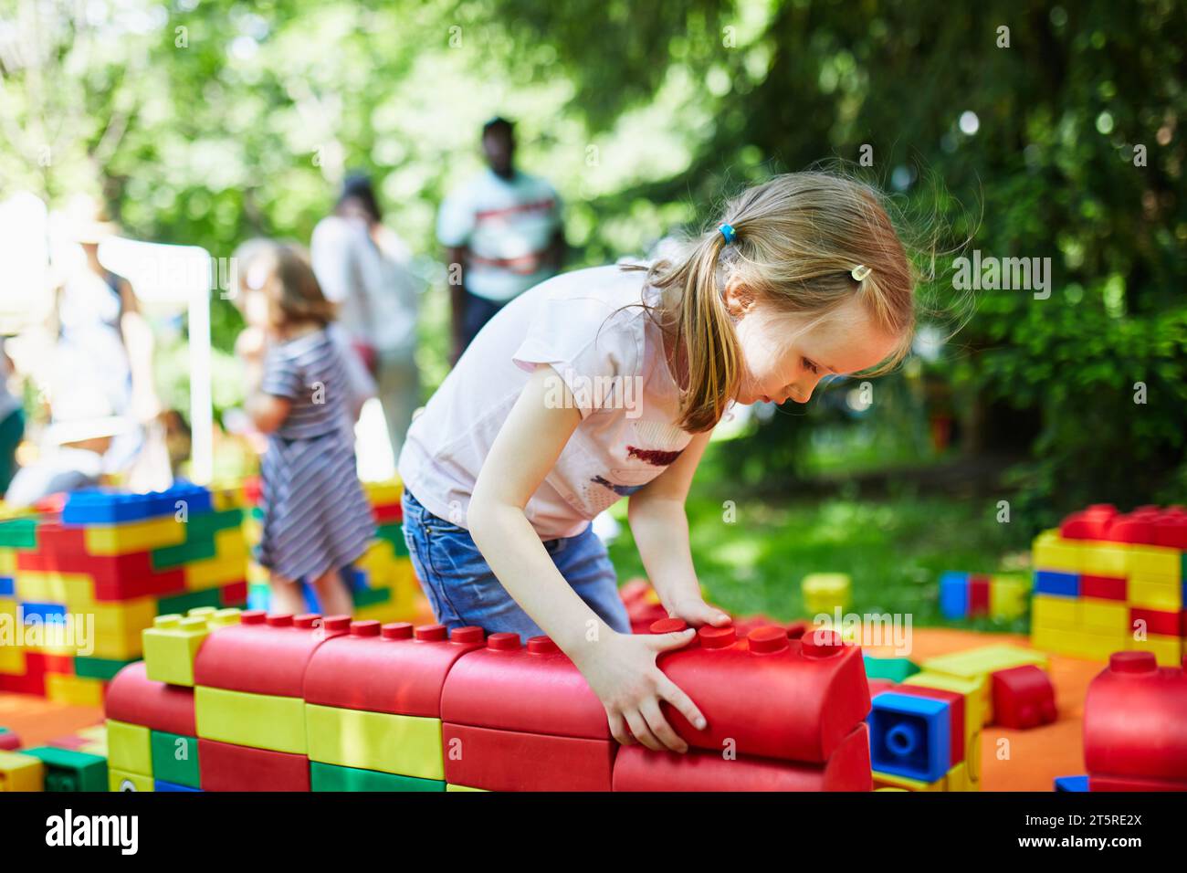 Adorable preschooler girl playing with large colorful plastic ...