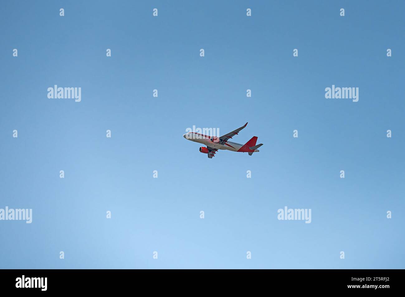 Red-coloured passenger plane in the sky Stock Photo - Alamy