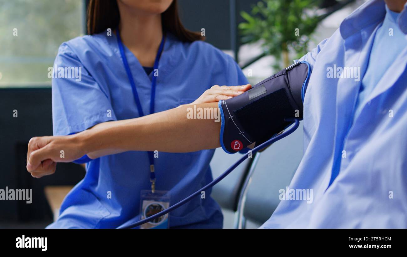 Assistant doing hypertension examination with tonometer in hospital ...