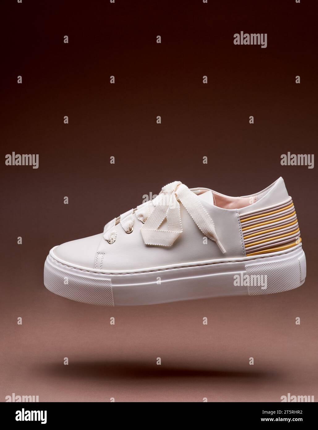 Close-up view of trendy everyday sneaker on the gradient brown ...