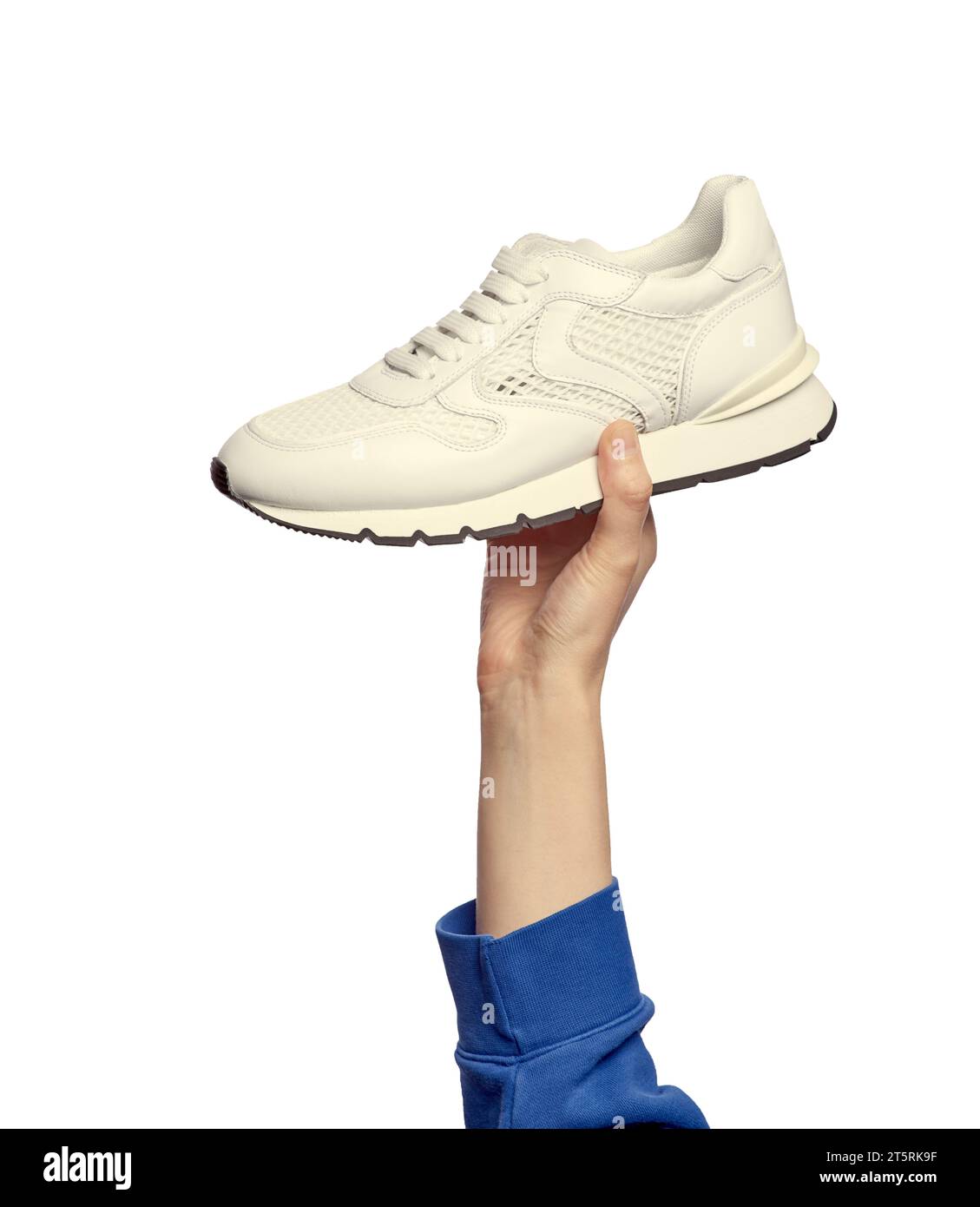 A woman's hand holding an ivory sneaker isolated on a white background ...