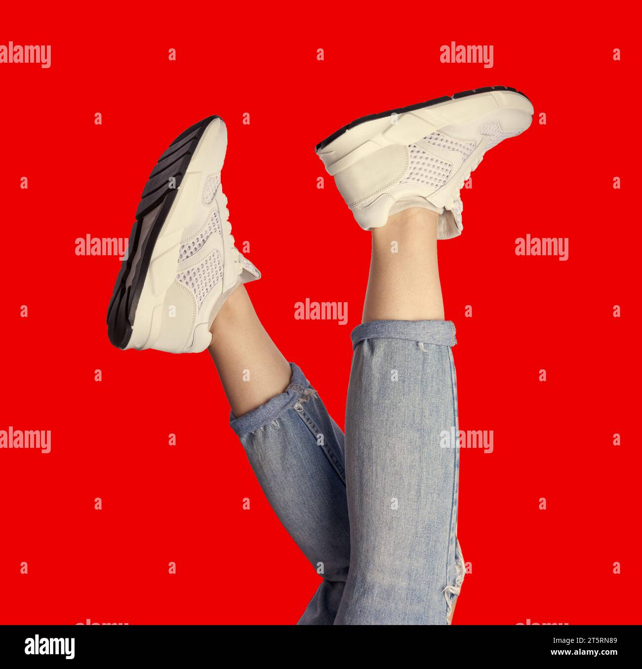 Female legs wearing trendy white sneakers and jeans isolated on a ...
