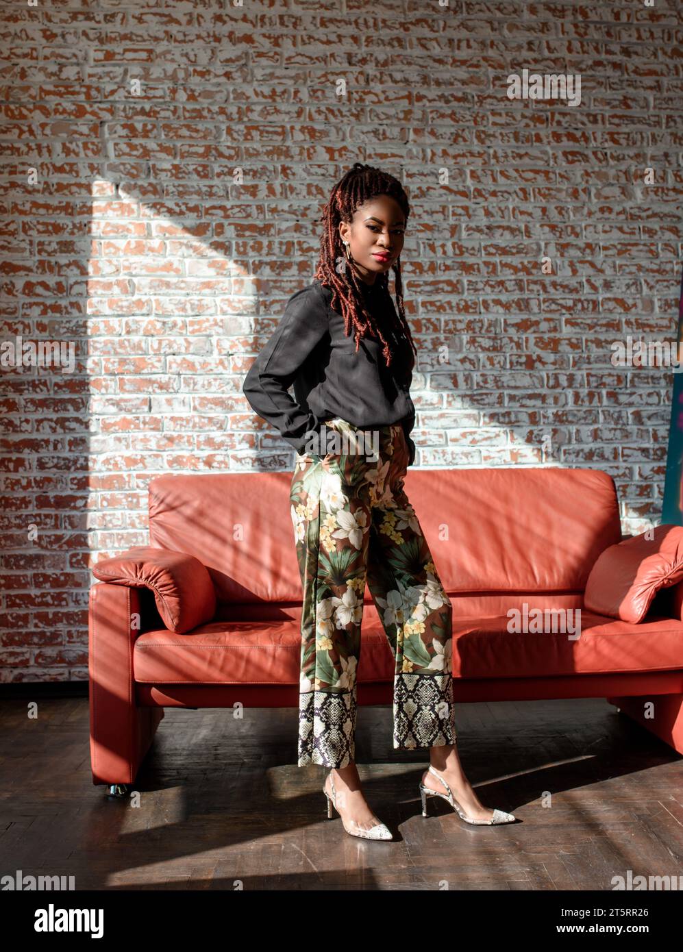 Confident black woman with dreads standing in the room against a red ...