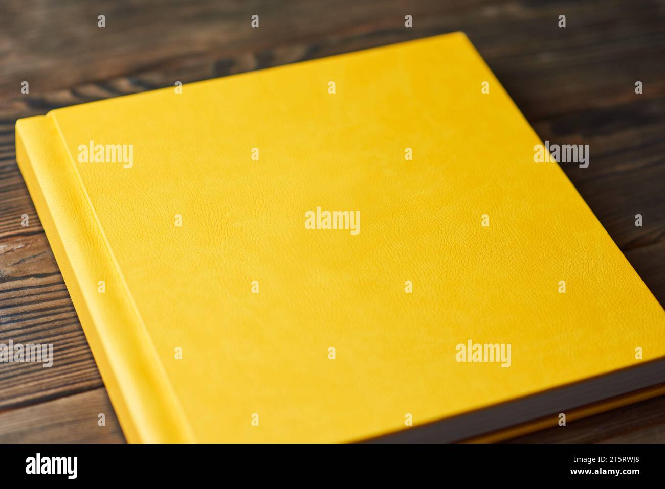 Photo album with bright yellow hardcover isolated on a brown wooden ...