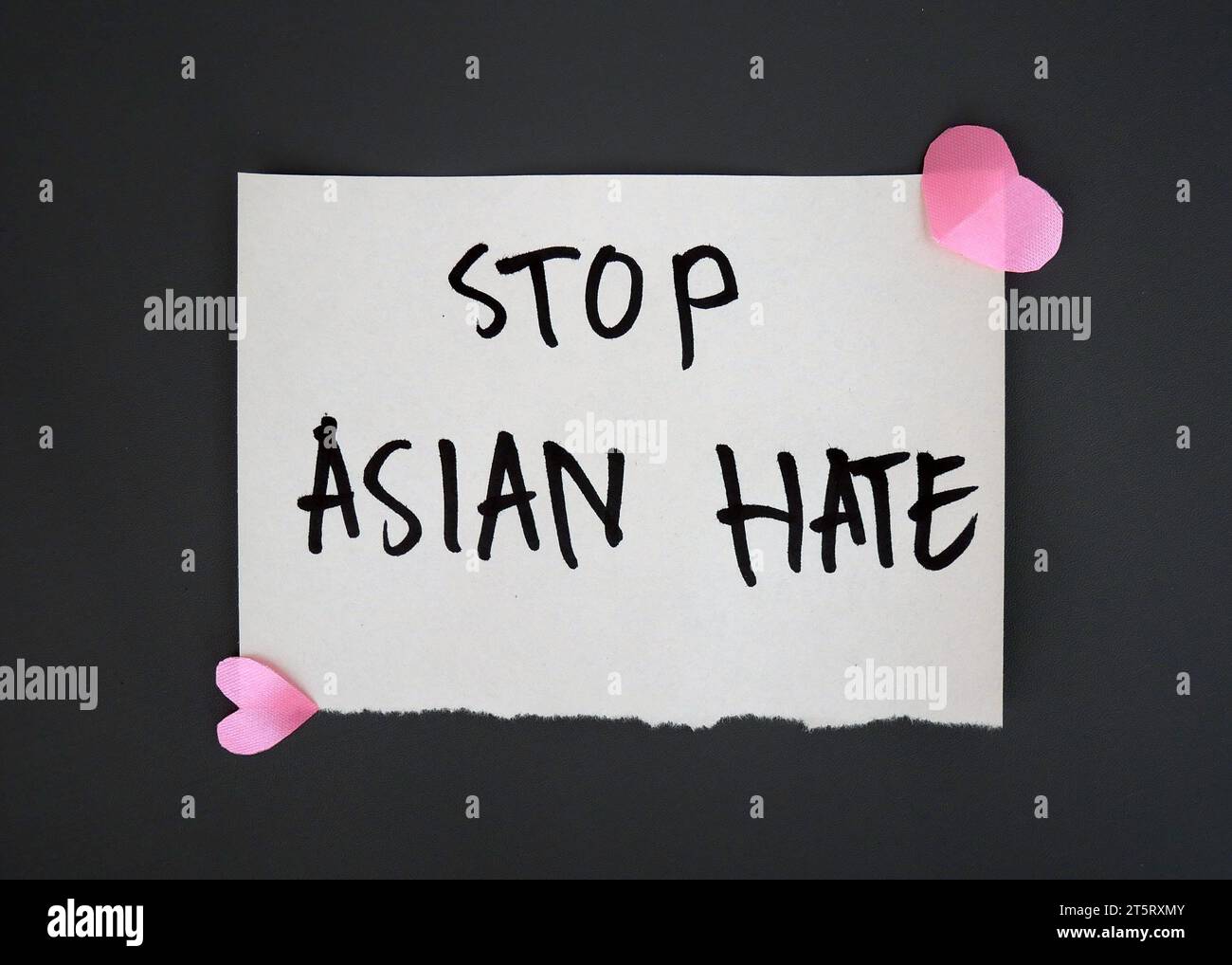 Paper with English words 'STOP ASIAN HATE' with pink heart in gray ...