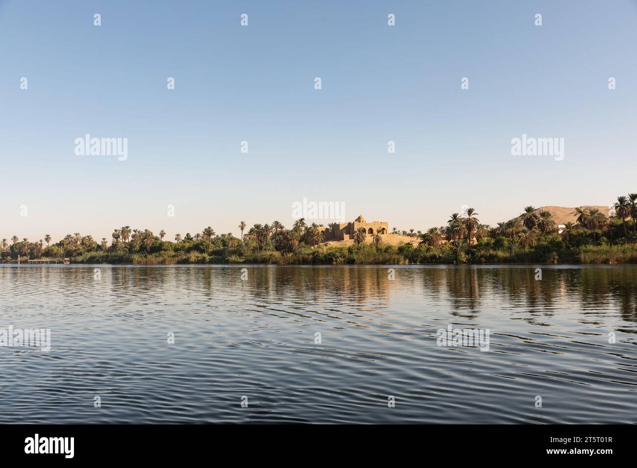Modern sandstone mansion surrounded by palm trees along banks of the ...