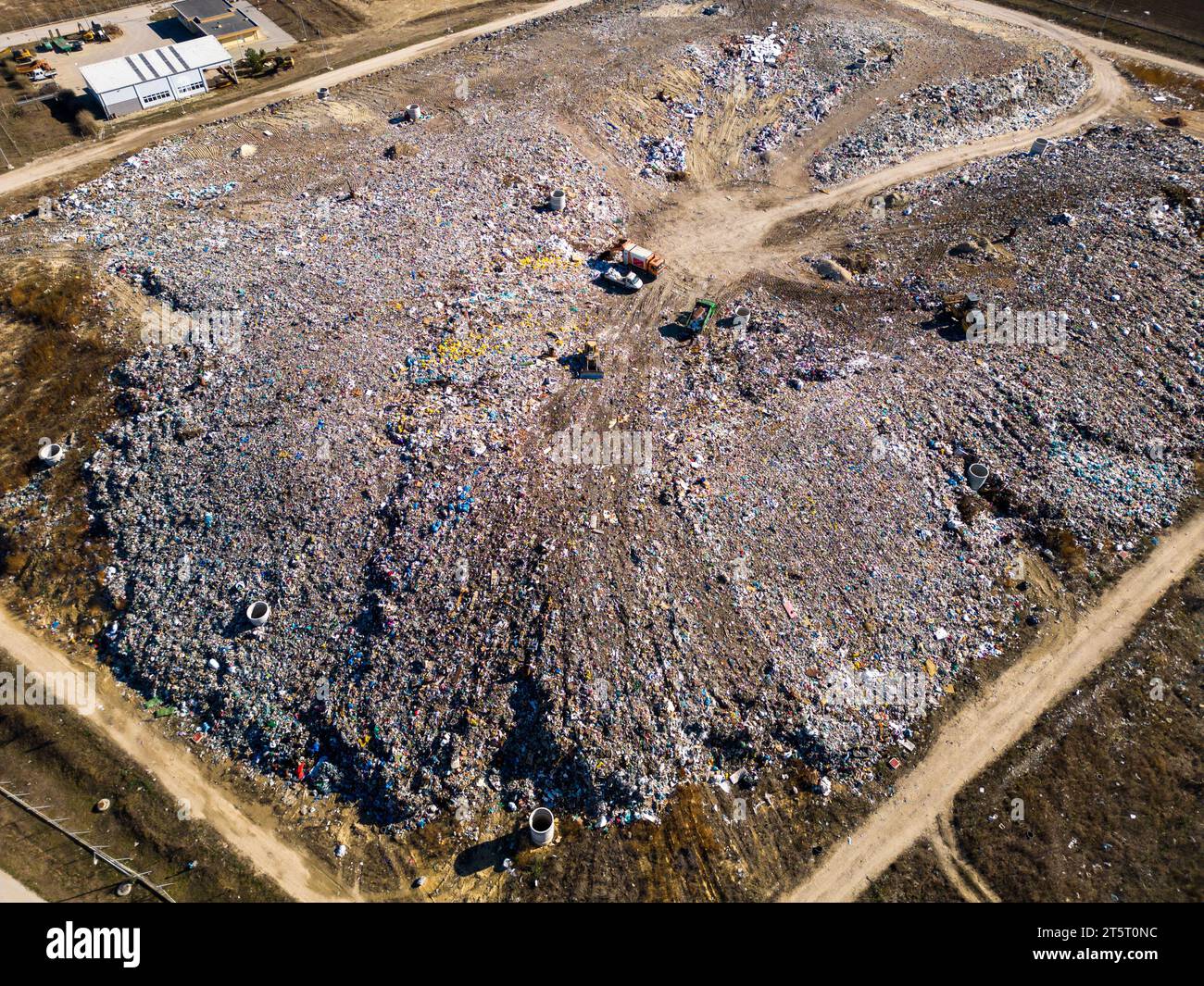 Aerial view of a vast landfill, where bulldozers are working and trucks ...