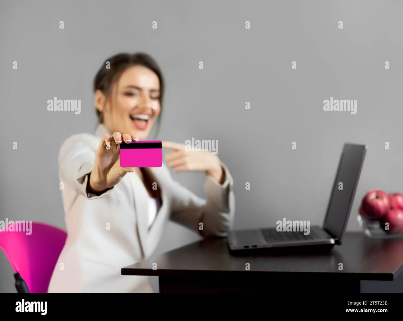 Beautiful woman smiling while showing a pink bank credit card in hand ...