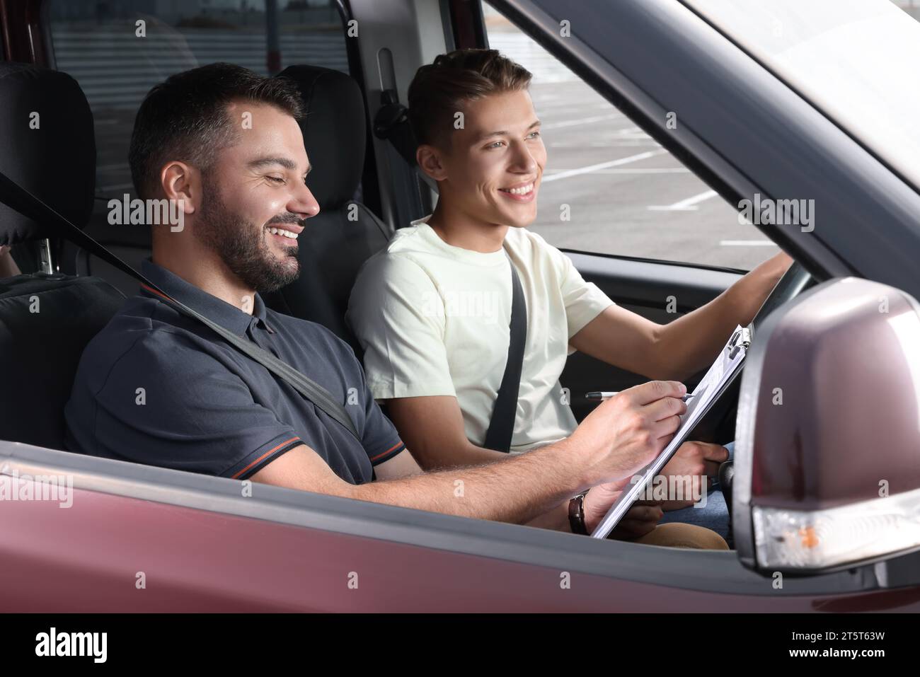 Driving school. Happy student passing driving test with examiner in car ...