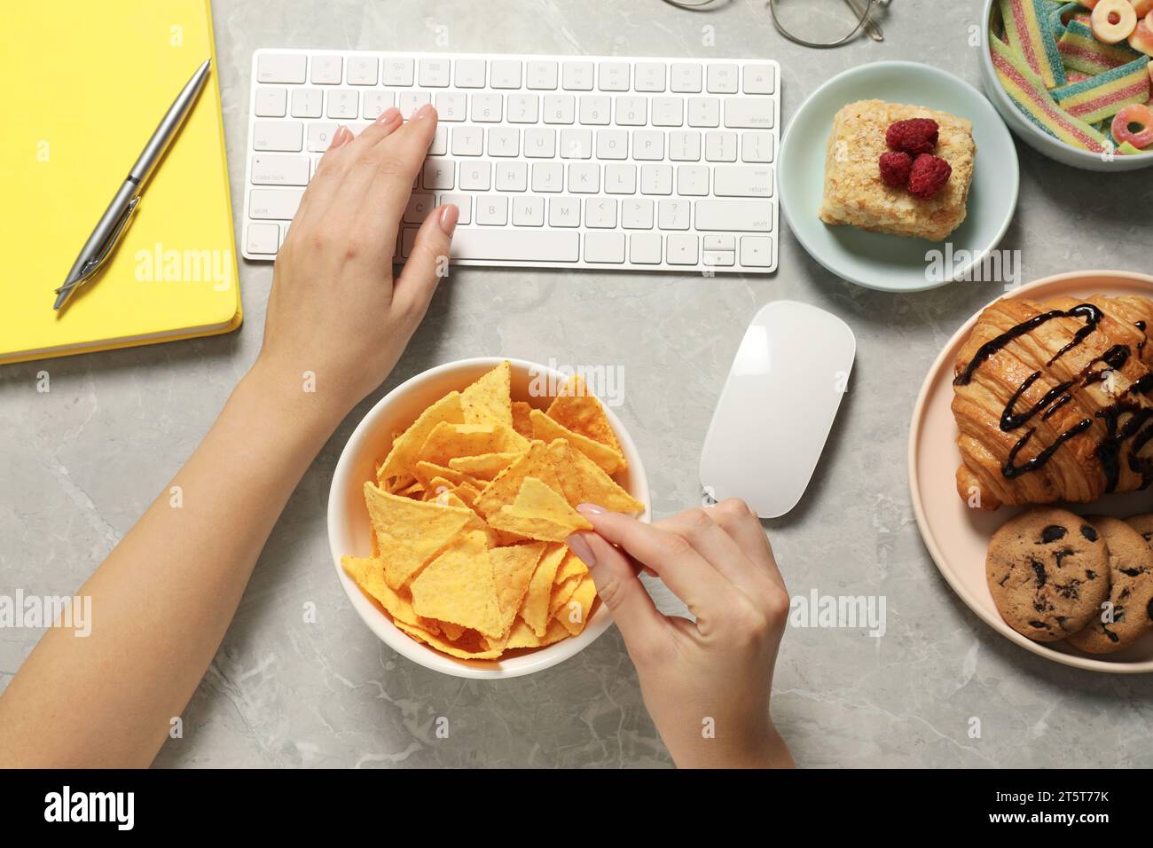 Bad habits. Woman eating different snacks while working on computer at ...