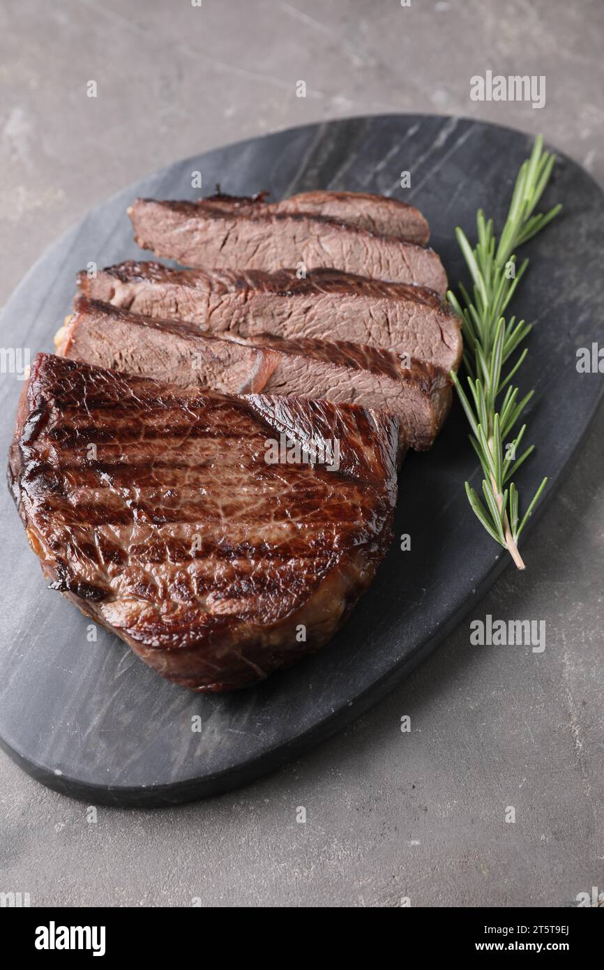 Delicious fried beef meat with rosemary on grey textured table Stock ...