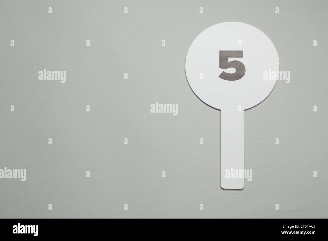 Auction paddle with number 5 on light grey background, top view. Space ...