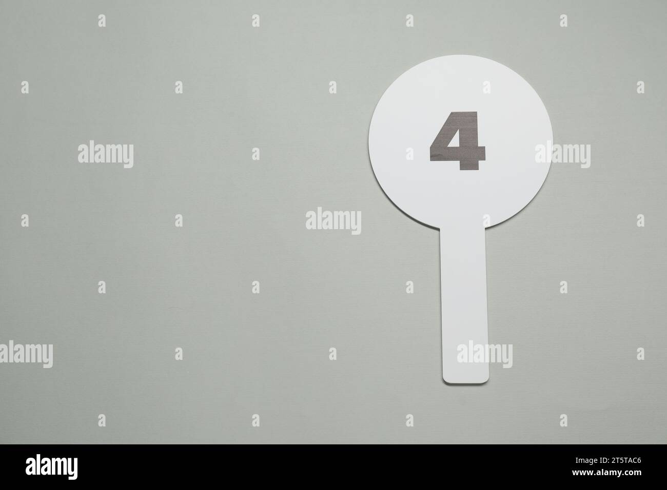 Auction paddle with number 4 on light grey background, top view. Space ...