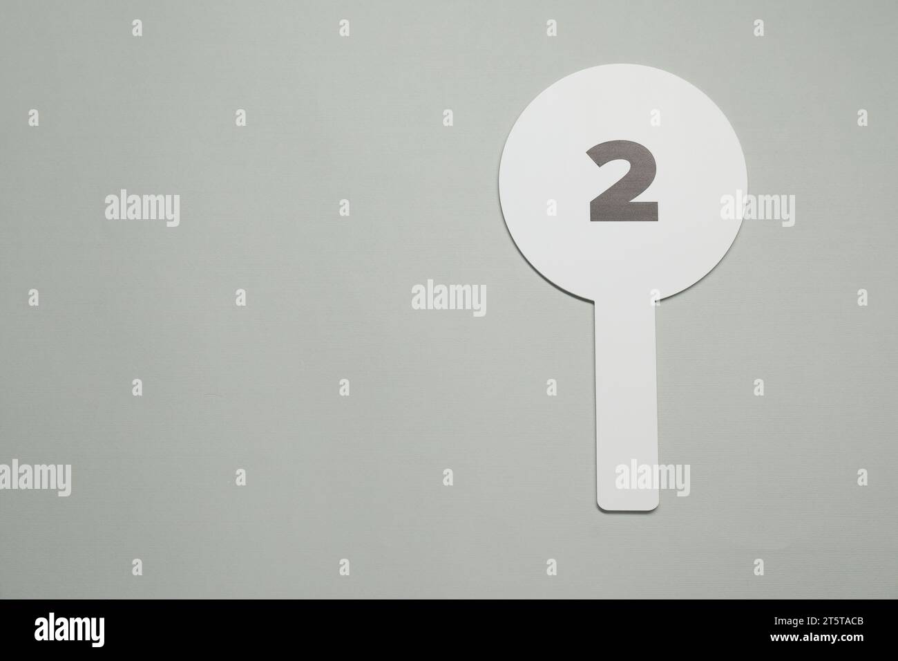Auction paddle with number 2 on light grey background, top view. Space ...