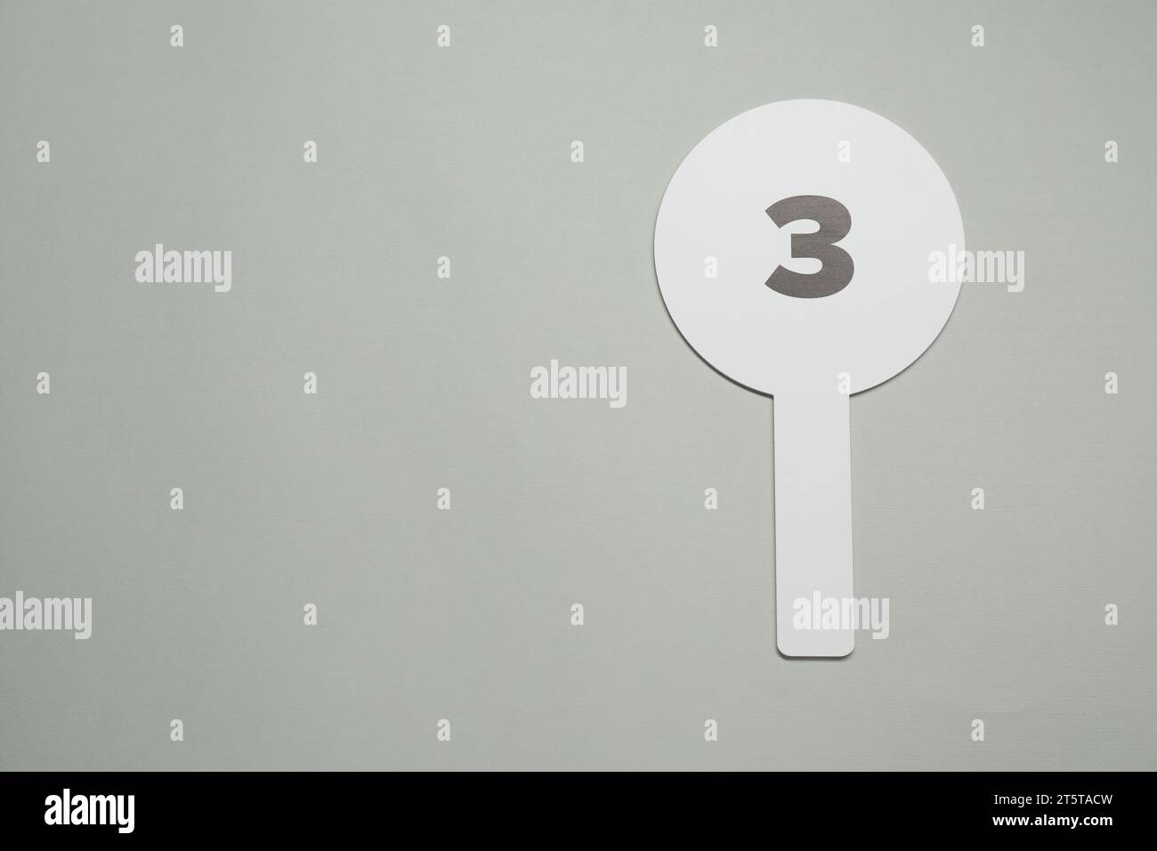 Auction paddle with number 3 on light grey background, top view. Space ...