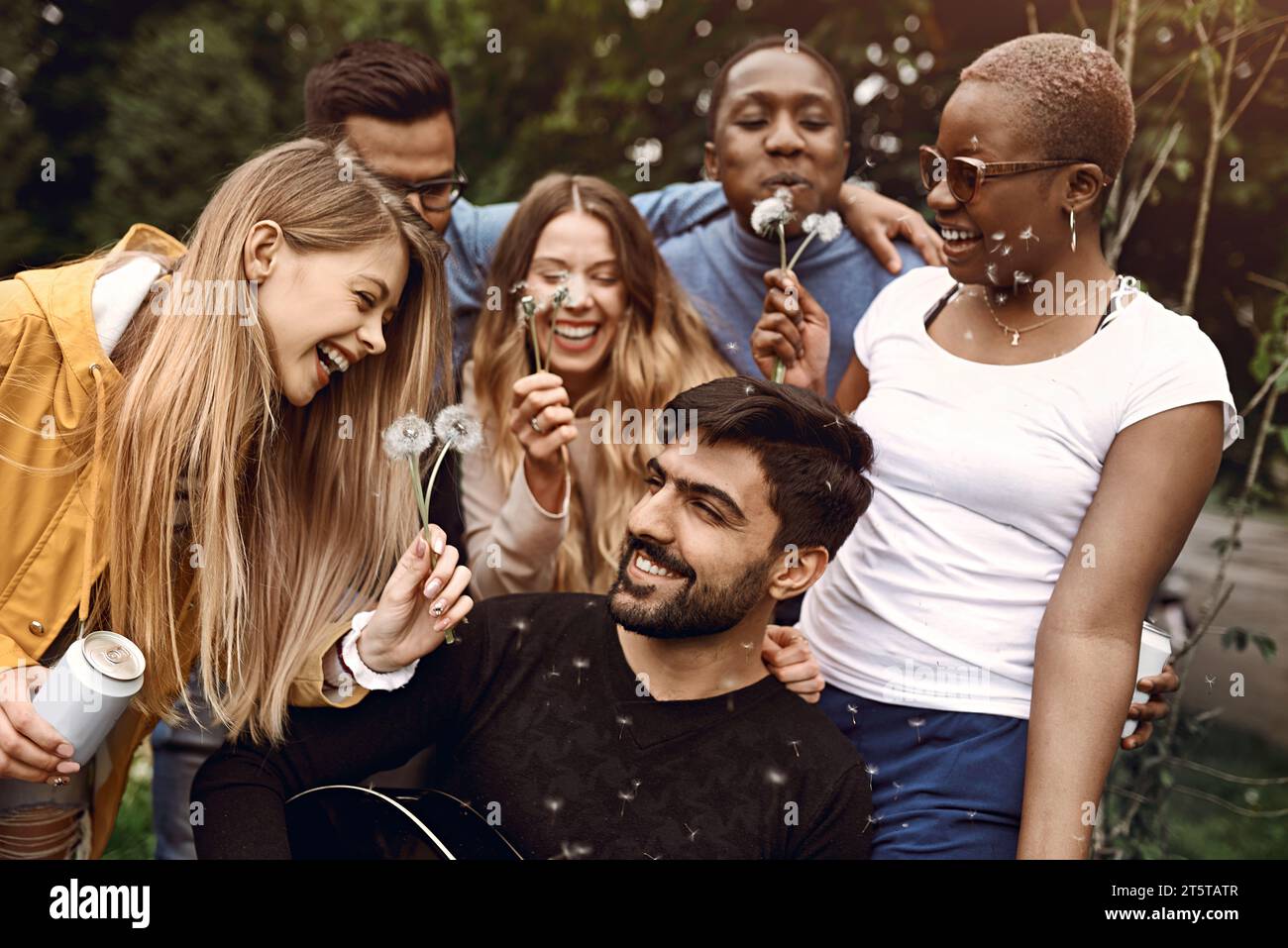 Bunch of happy joyful friends blowing dandelions and laughing. Mixed ...