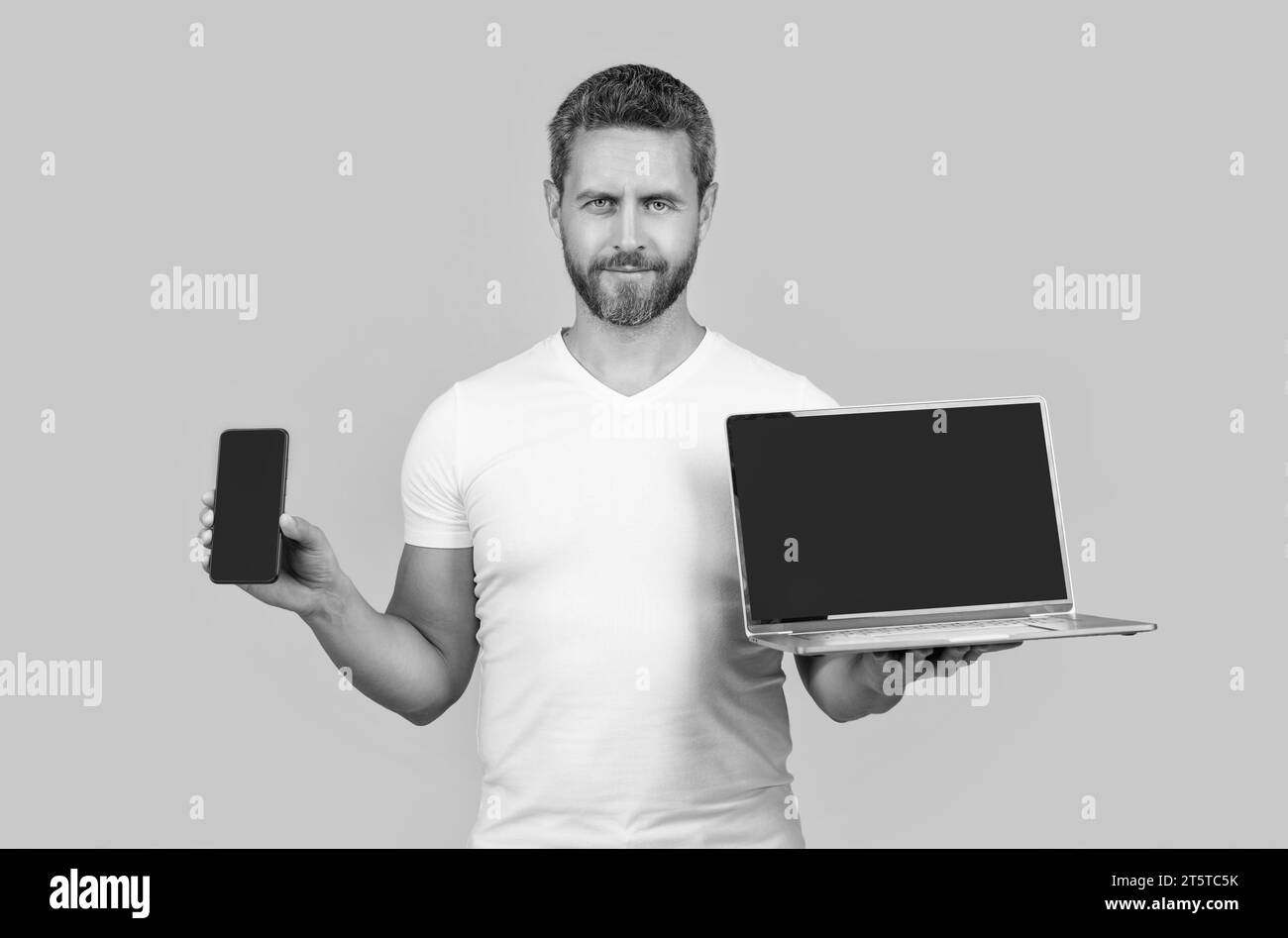 guy showing smartphone and laptop screen in studio. guy showing screen ...