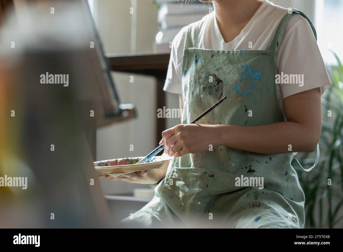 Female artist hold color palette and paintbrush for painting during ...