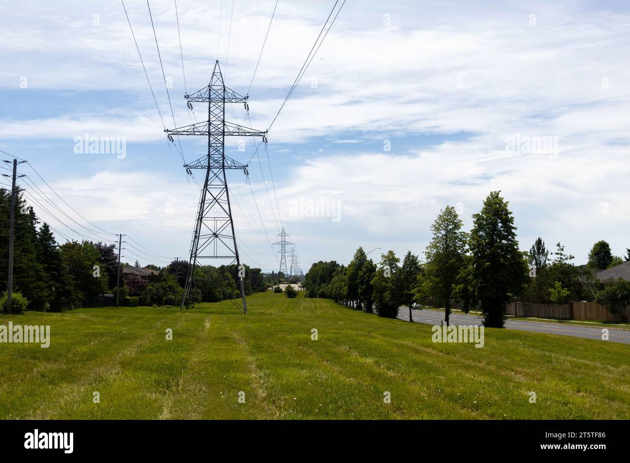 Power lines - green field - blue sky - suburban neighborhood Stock ...