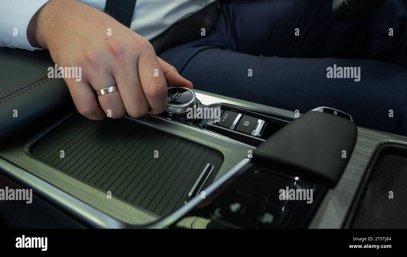 Close-up of a man's hands on the automatic transmission of a modern car ...