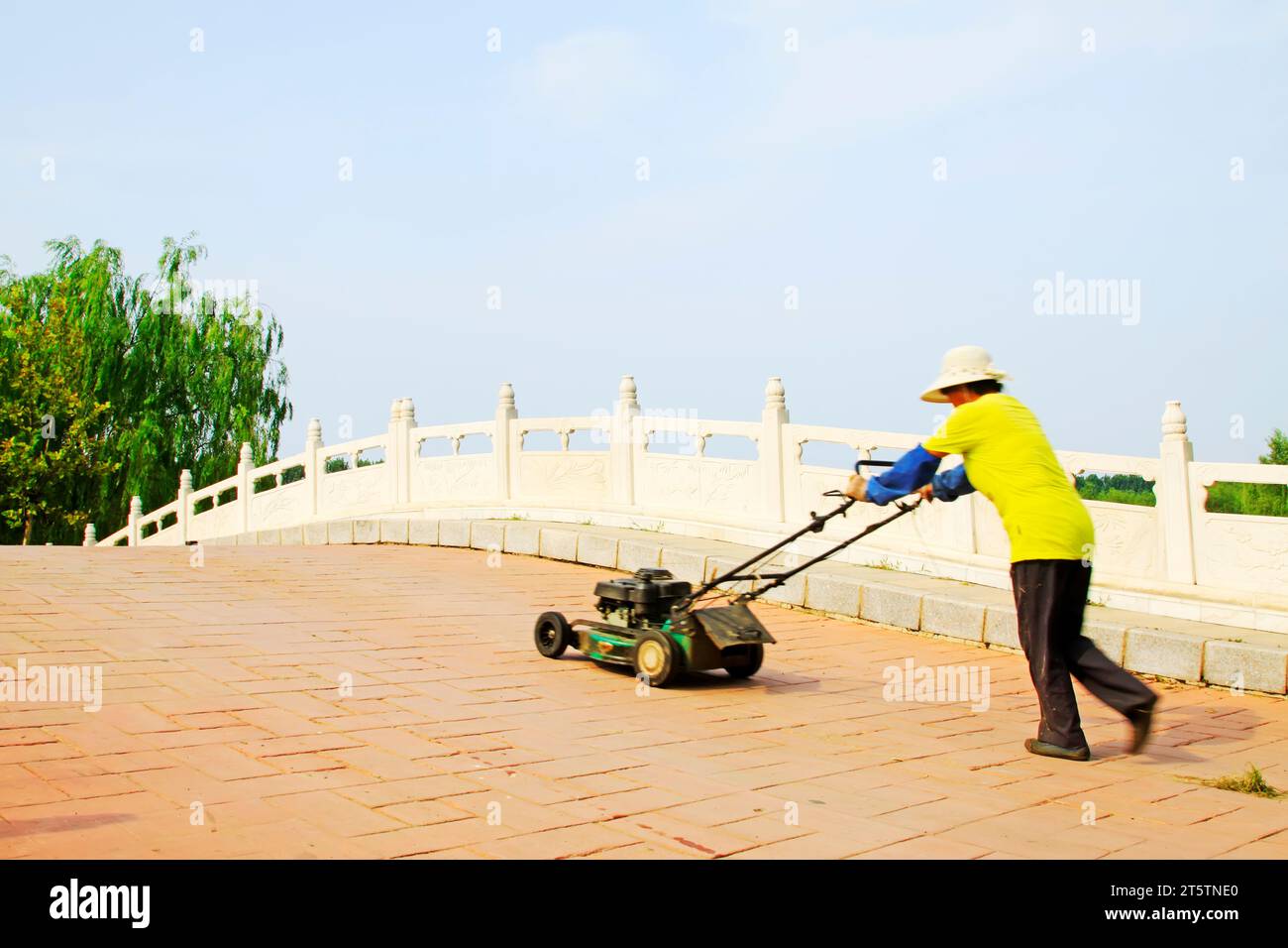 Workers push lawn mower through the bridge Stock Photo - Alamy