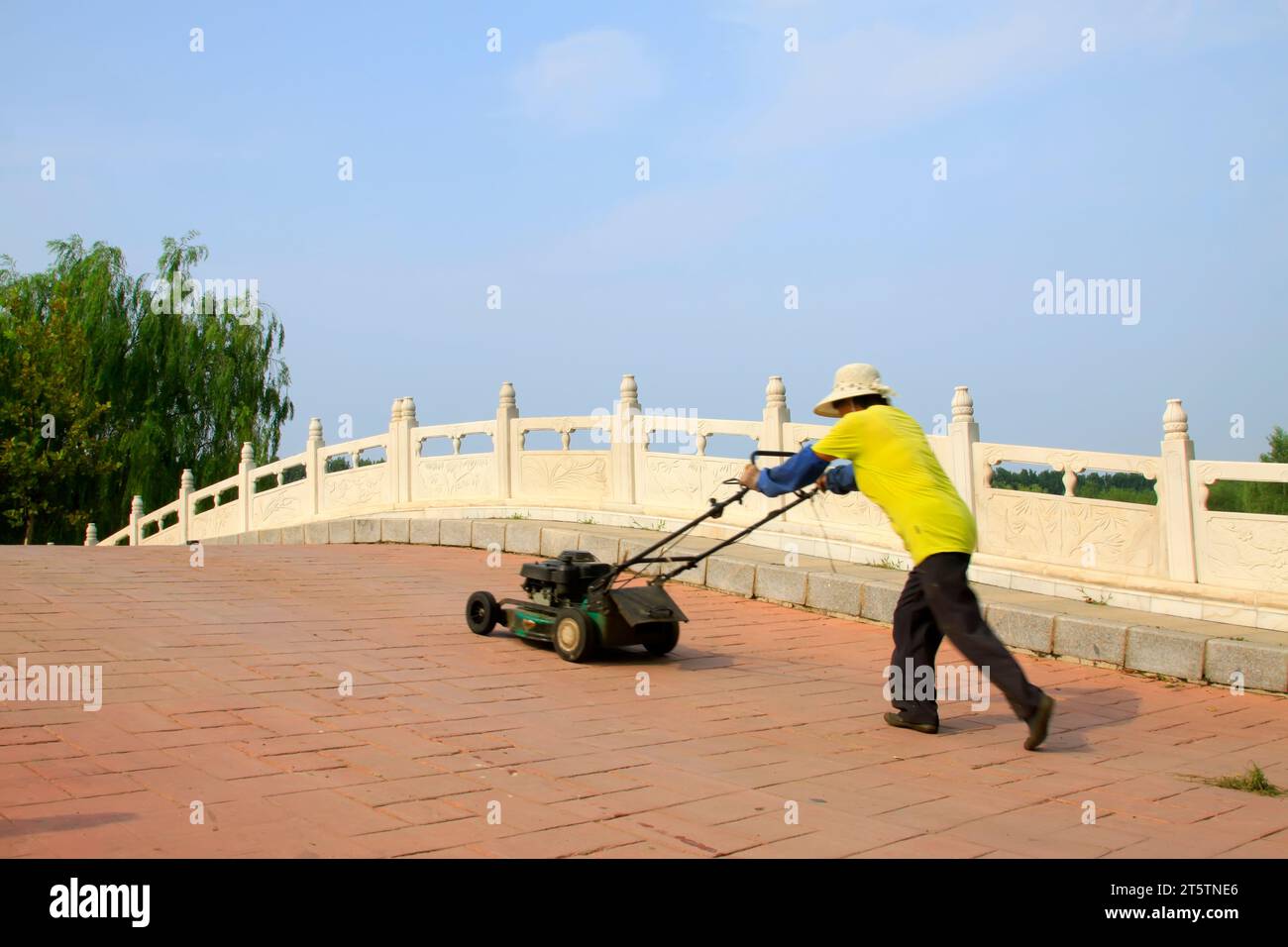 Workers push lawn mower through the bridge Stock Photo - Alamy