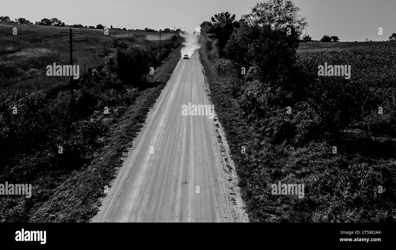 Looking down a gravel road with dust being blown by a vehicle. Path ...