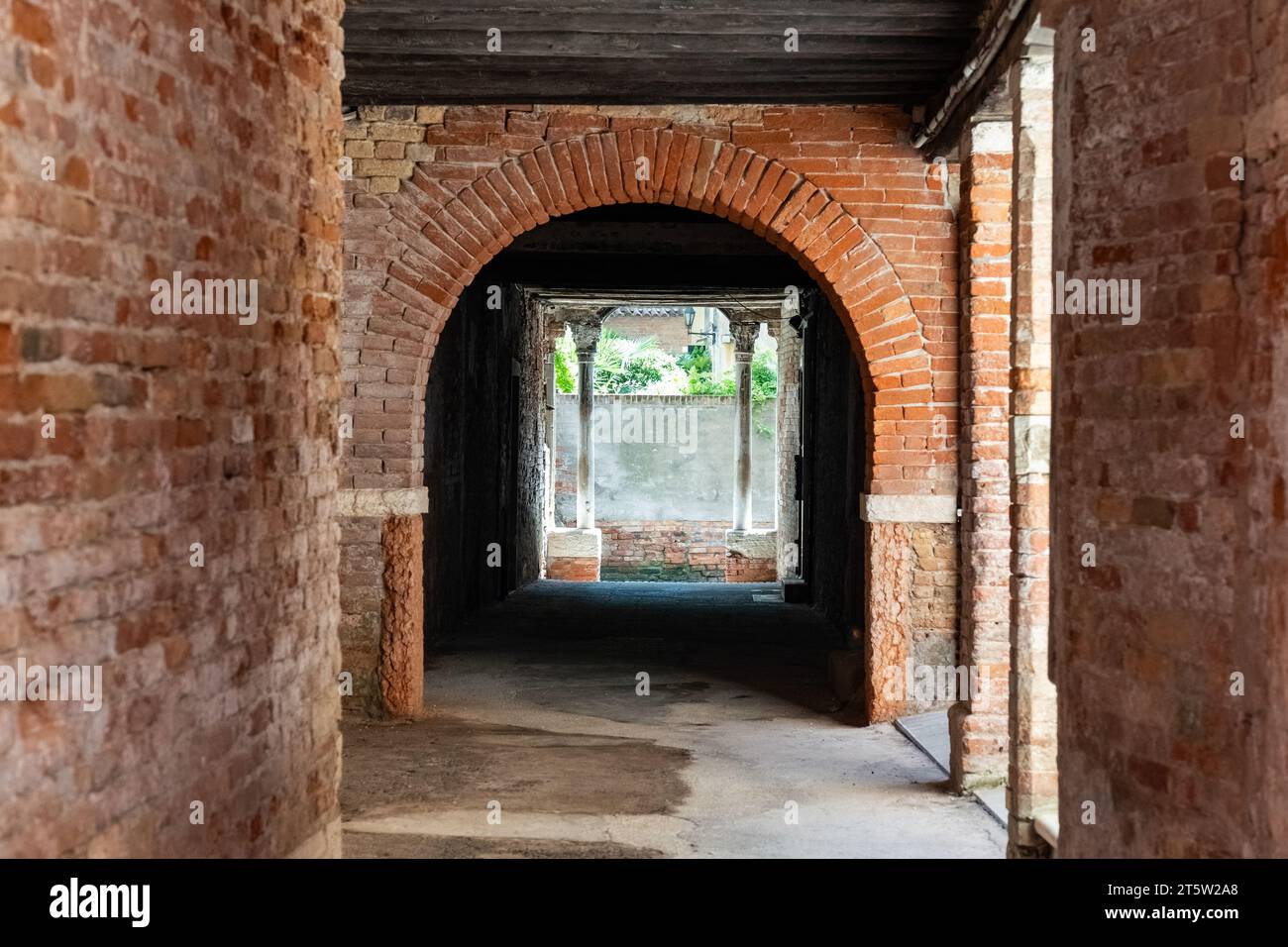 Old, empty arched hall or passage made of bricks with wooden beams in ...