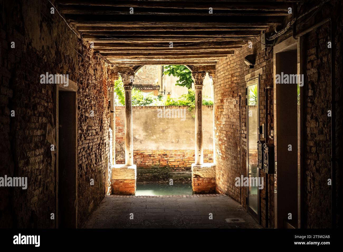 Old, empty arched hall or passage made of bricks with wooden beams in ...