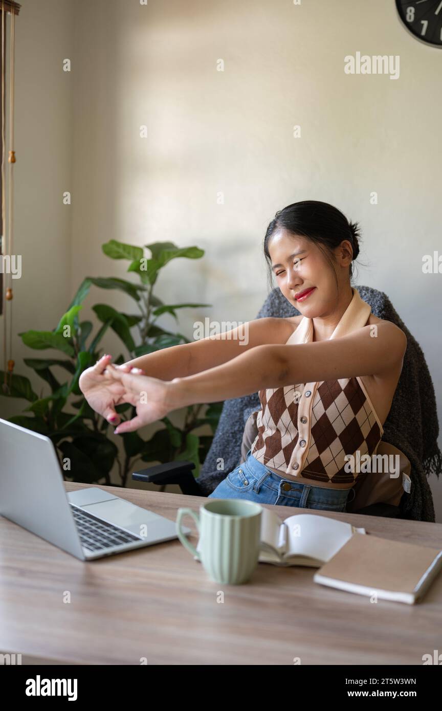 A beautiful Asian woman is stretching her arms to relax after finishing ...