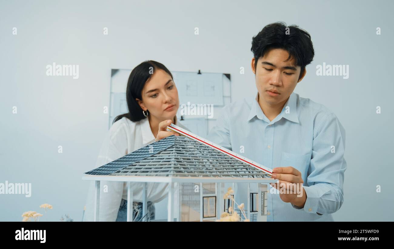 Professional young beautiful architect engineer using ruler and pencil measuring model roof ...