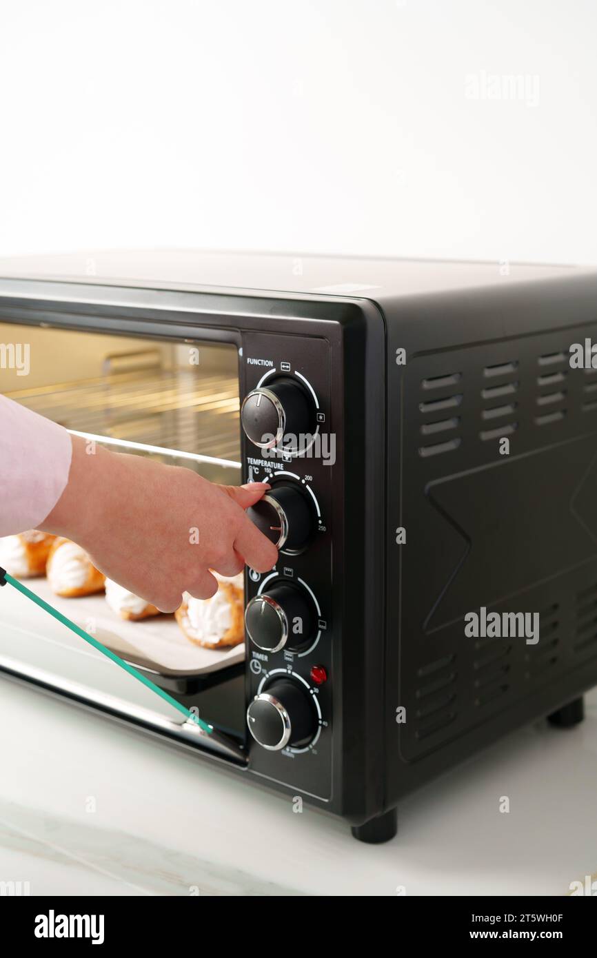 Woman's hands taking fresh bakery out of mini oven Stock Photo - Alamy
