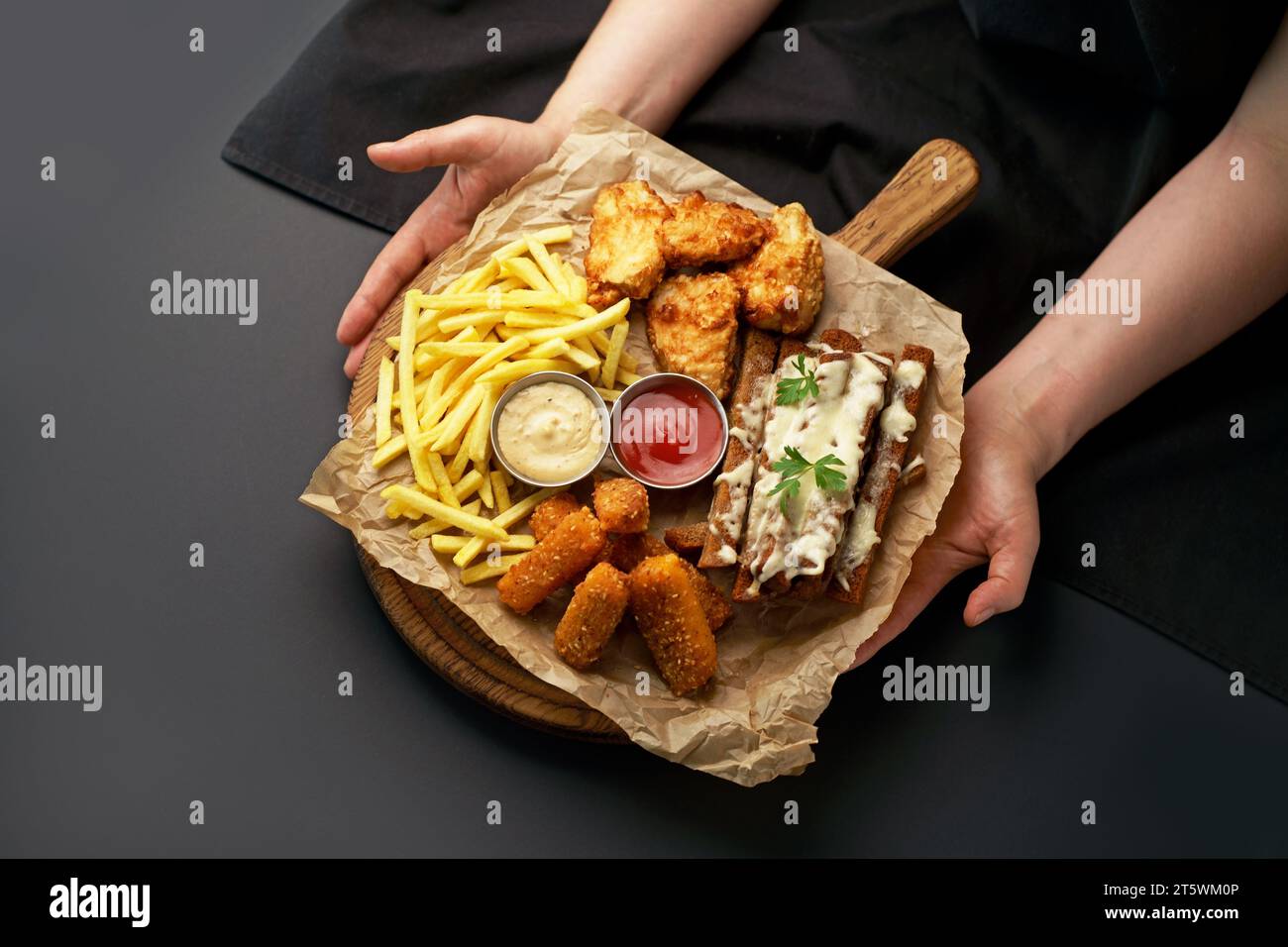 chicken fillet fried in batter with sauce on a wooden board on a black ...