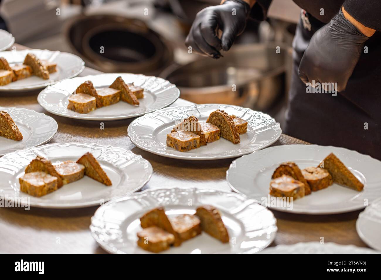 Chef plating slices of toasted bread and ground meat on white plates ...