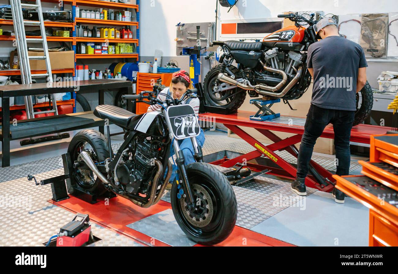 Mechanic couple repairing custom motorcycles on factory Stock Photo - Alamy