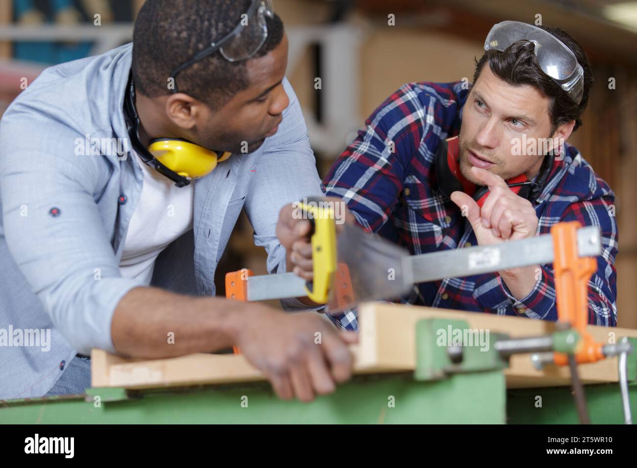 carpenter training male apprentice to use mechanized saw Stock Photo ...