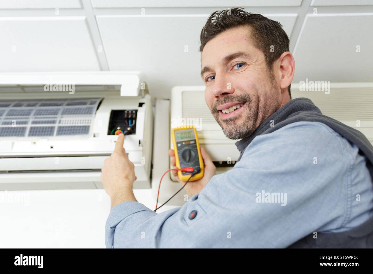 male electrician checking air conditioner with digital multimeter Stock ...