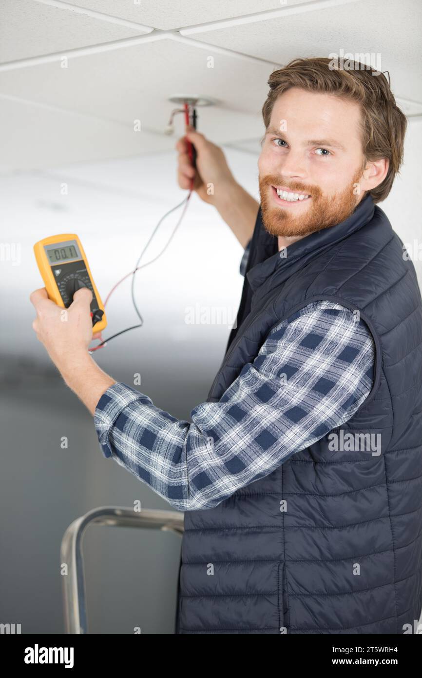 electrician on ladder measuring electrical current Stock Photo - Alamy