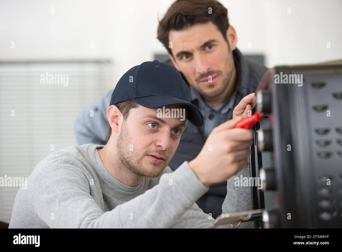 two men fixing oven in kitchen Stock Photo - Alamy
