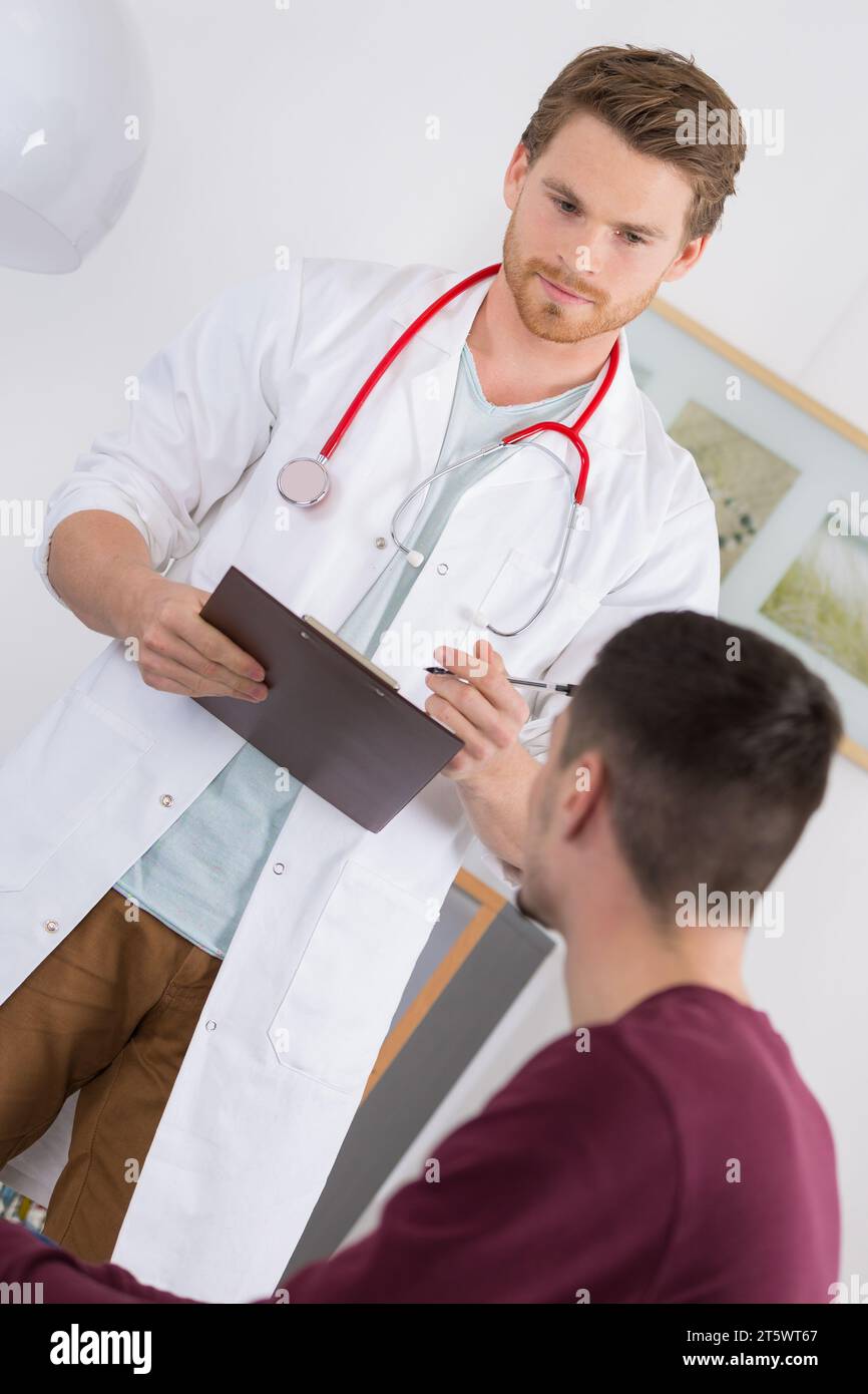 doctor with patient filling out paperwork on clipboard Stock Photo - Alamy