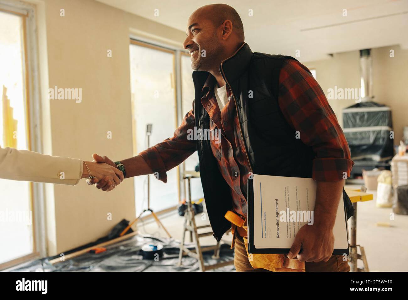 Happy mature contractor shakes hands with a homeowner after signing the ...
