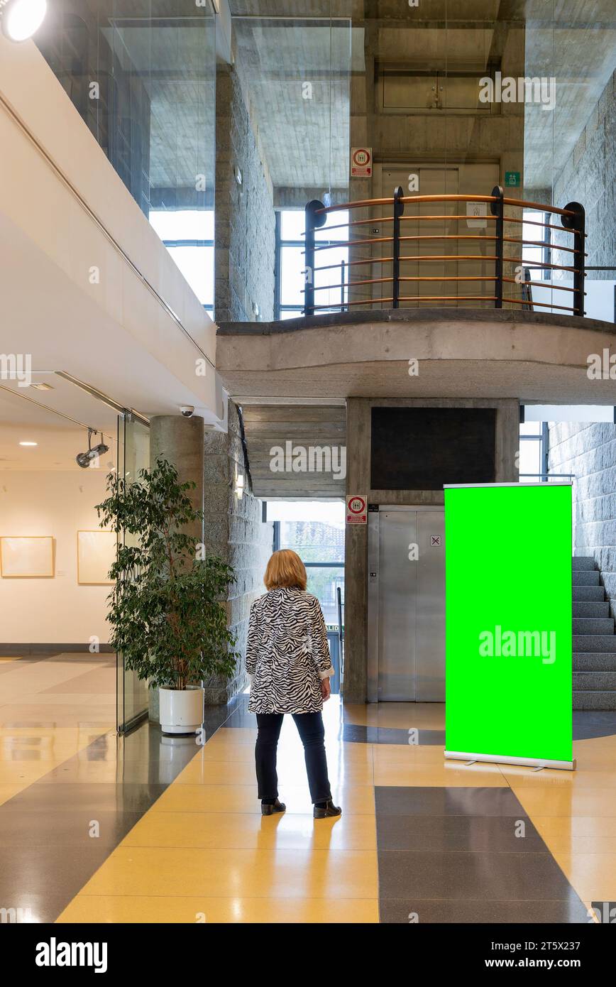 Woman inside a modern building looking at a custom roll up. Banner ...