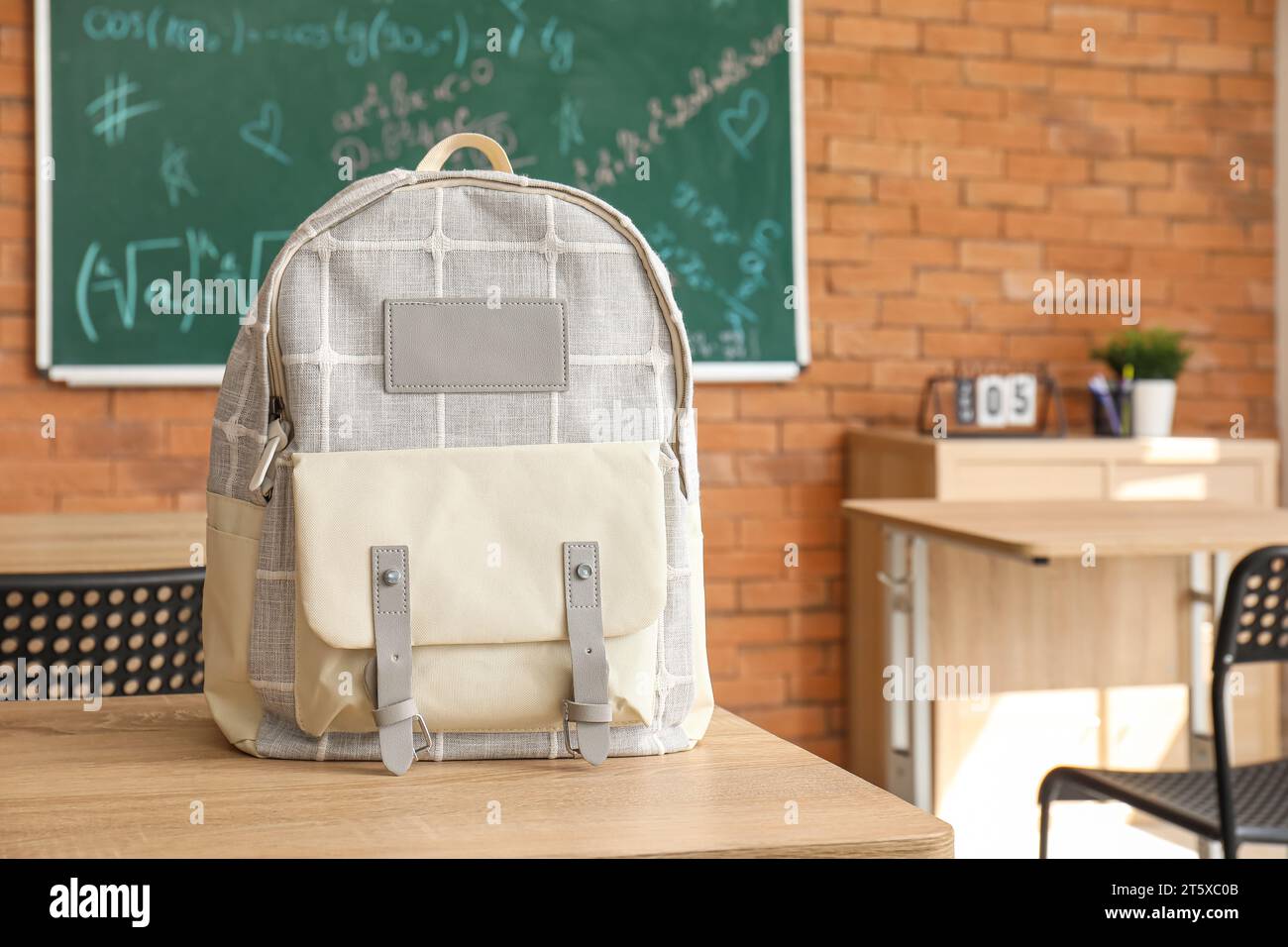 Stylish school backpack on desk in classroom Stock Photo - Alamy
