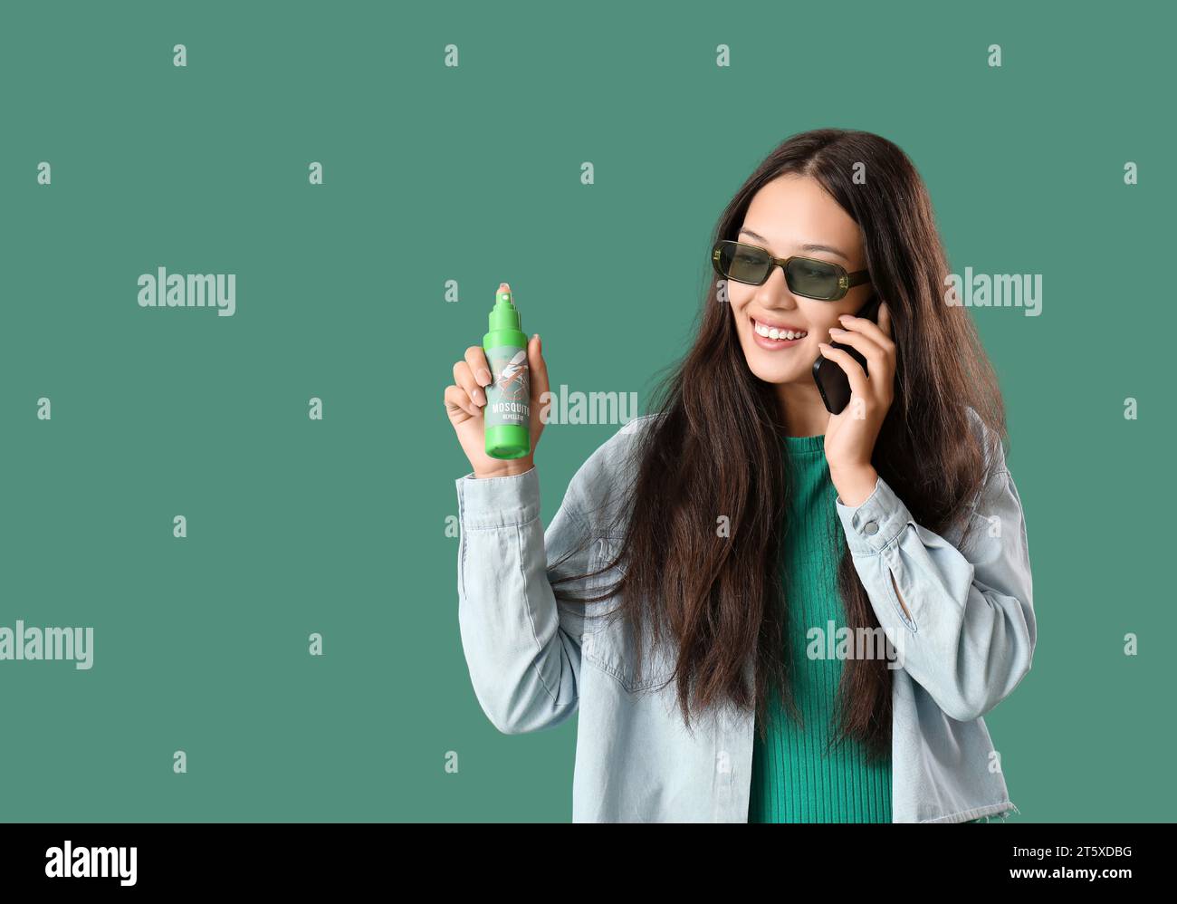 Beautiful young Asian with mosquito repellent spray talking by mobile ...