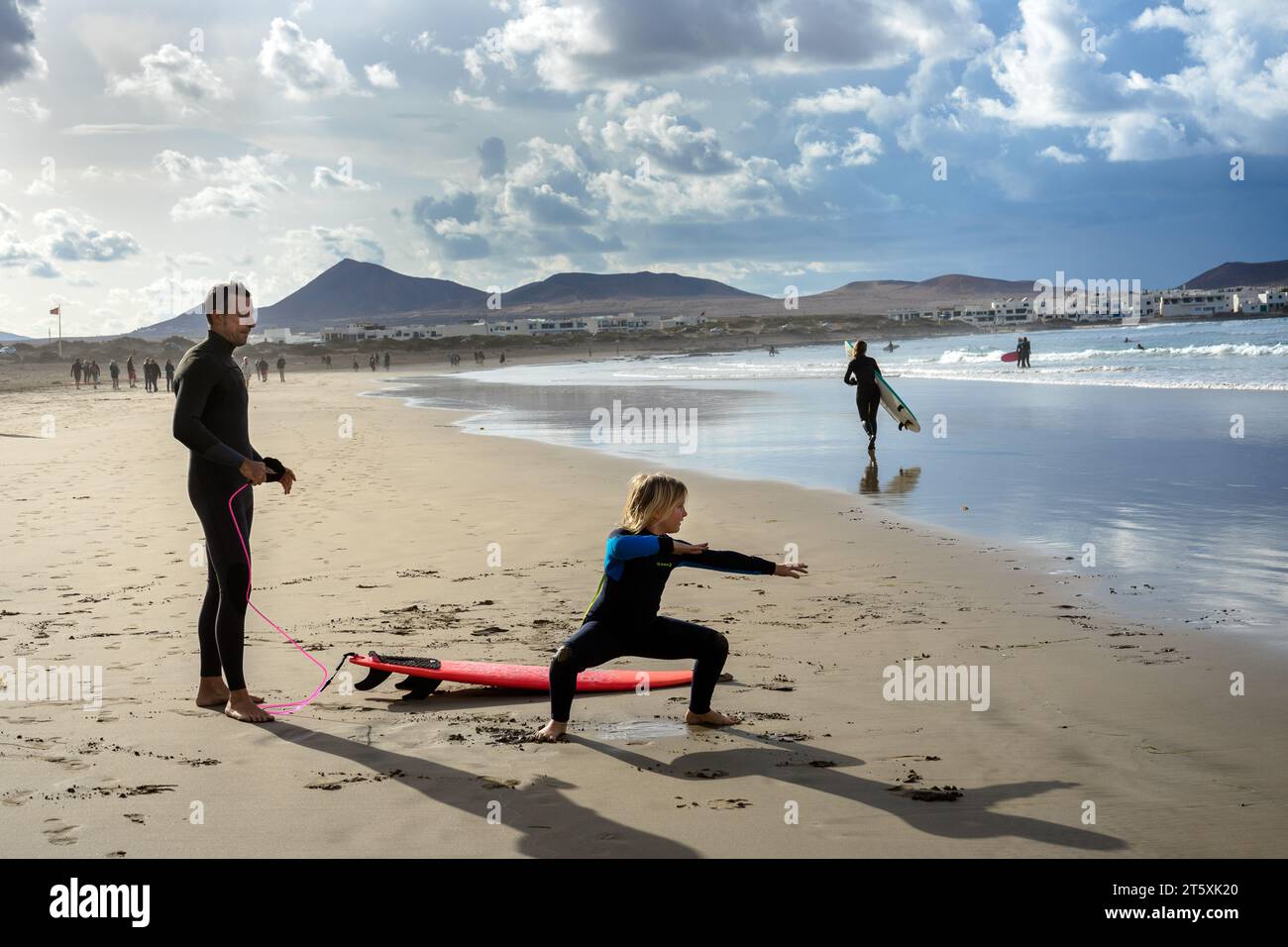 Spain, Lanzarote, Caleta de Famara: the father teaches his son to surf ...